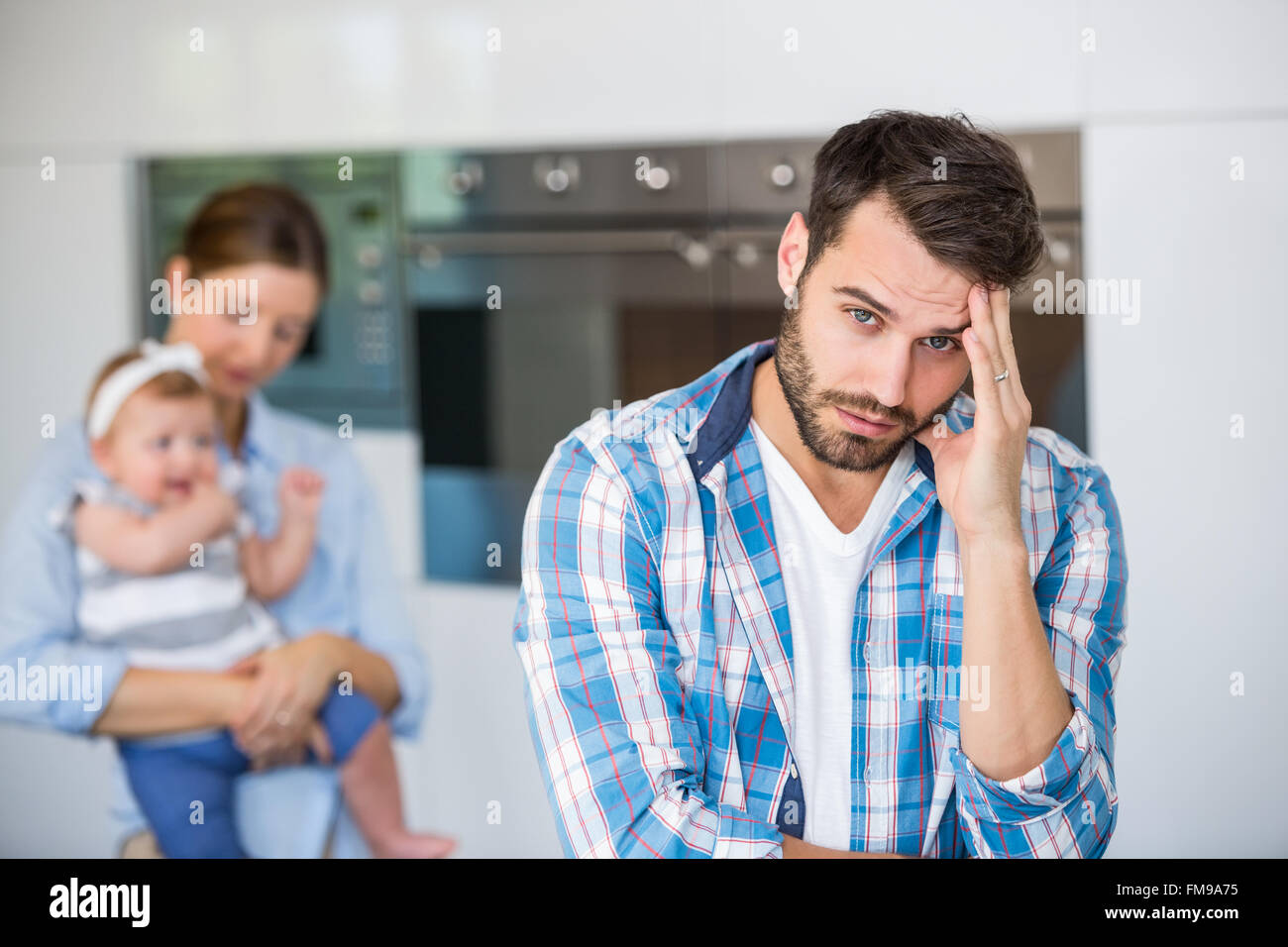 Tensed man with wife and baby in background Stock Photo - Alamy