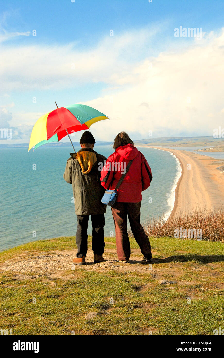 Older couple with a rainbow umbrella, look out over the elevated view ...