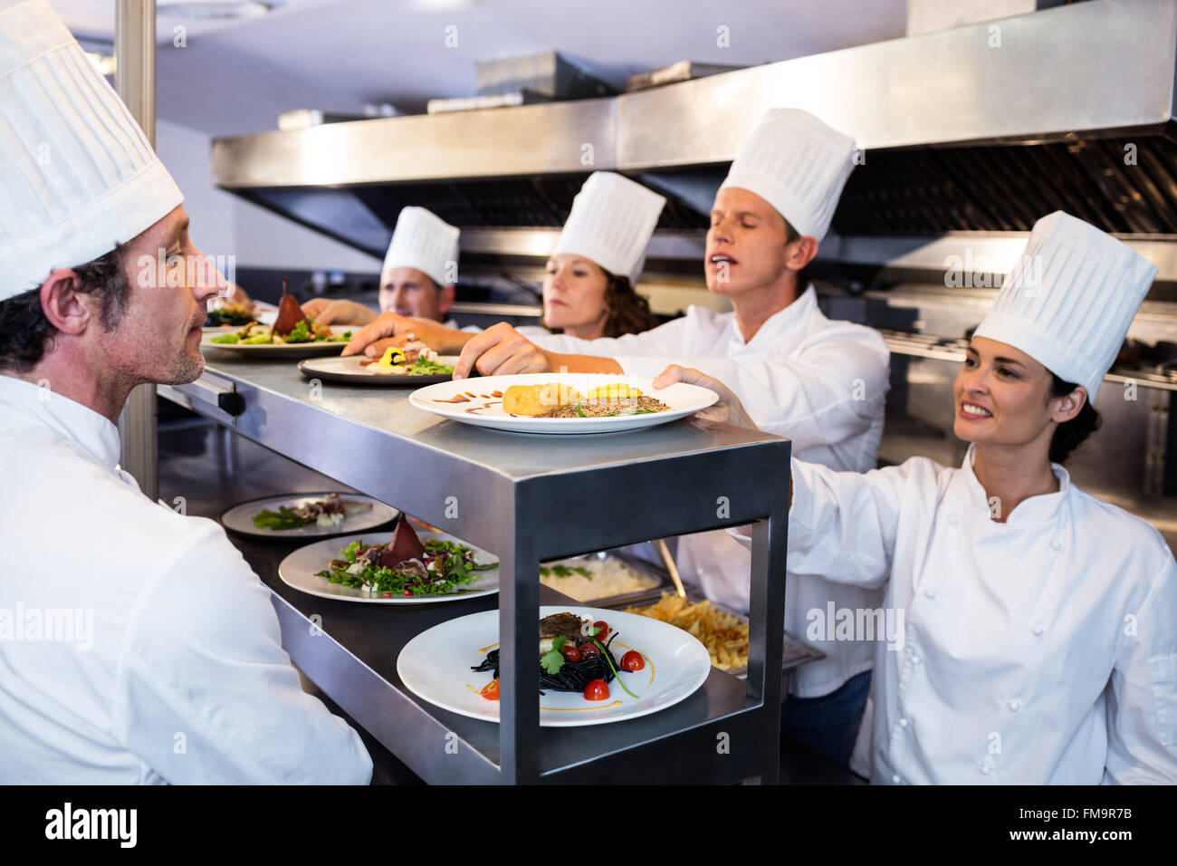 Chefs handing dinner plates through order station Stock Photo - Alamy