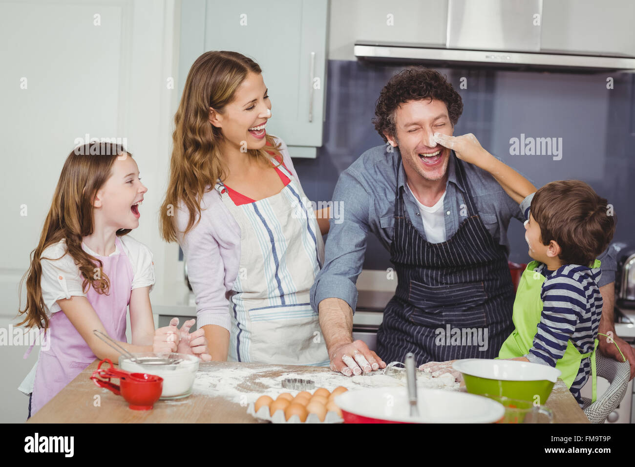 Happy family enjoying while cooking food Stock Photo - Alamy
