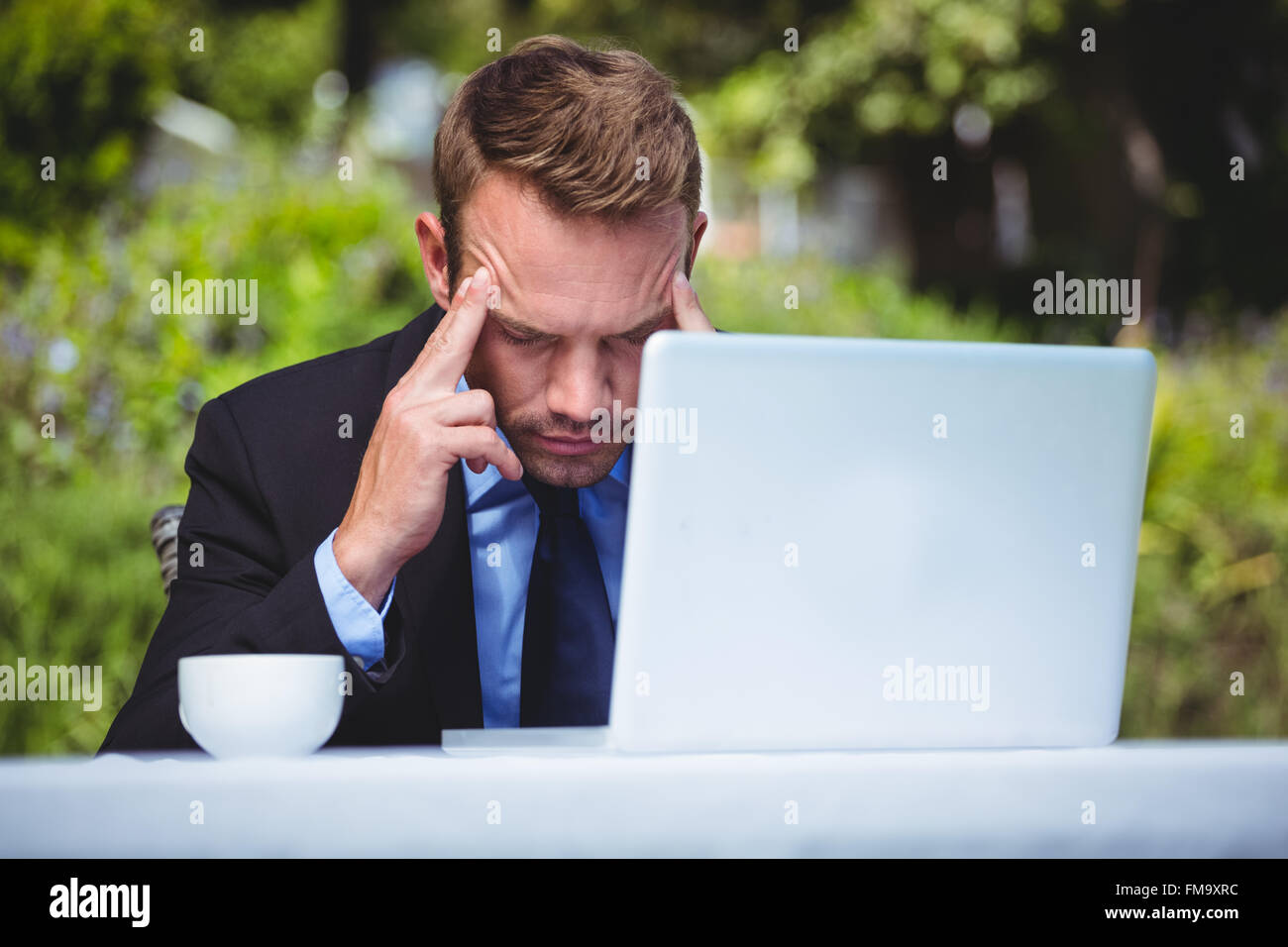 Businessman using laptop having a headache Stock Photo - Alamy