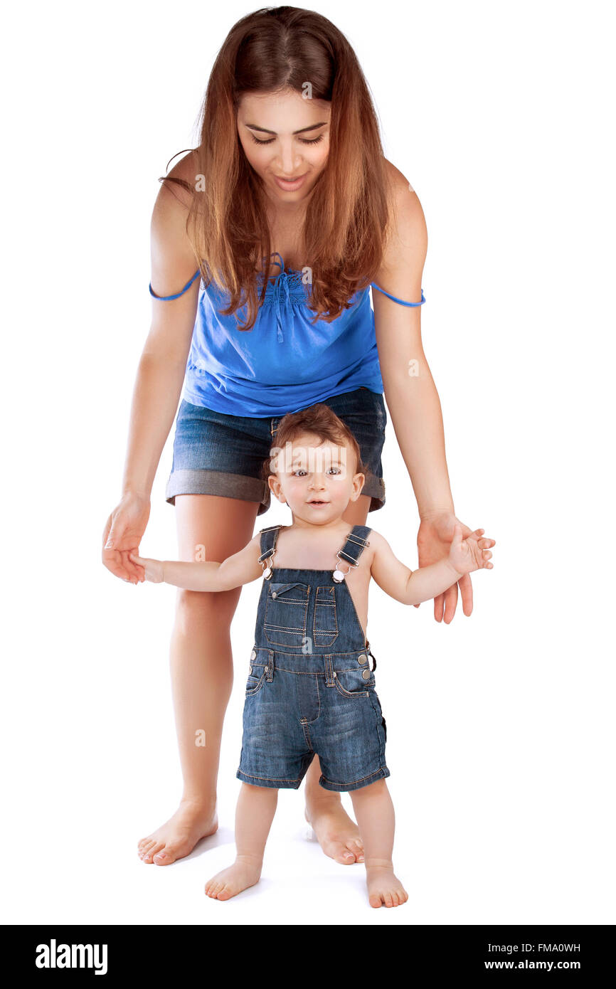 Mother helping her little son doing his first steps, holding hands and ...
