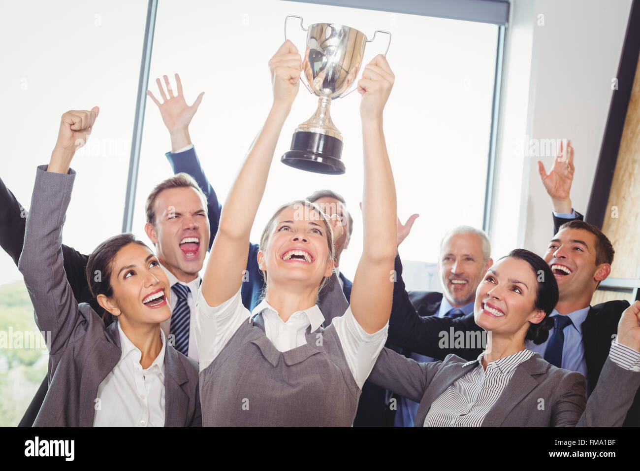 Winning business team with an executive holding trophy Stock Photo - Alamy
