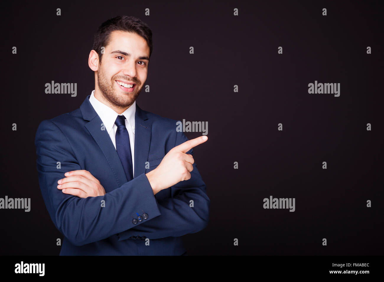 Handsome businessman pointing at copyspace on black background Stock ...