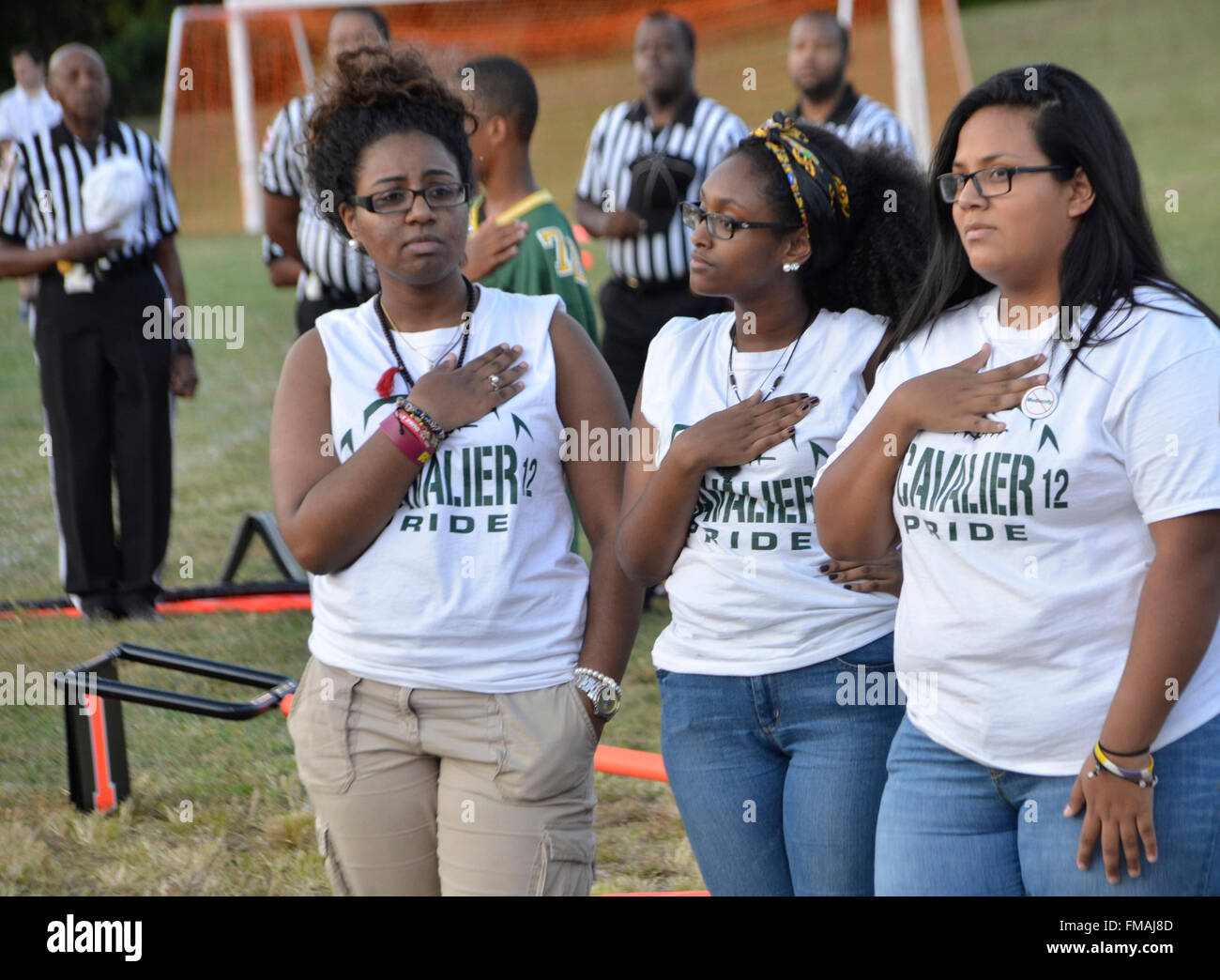 3 girls hold their hands over their heart during the playing of the ...
