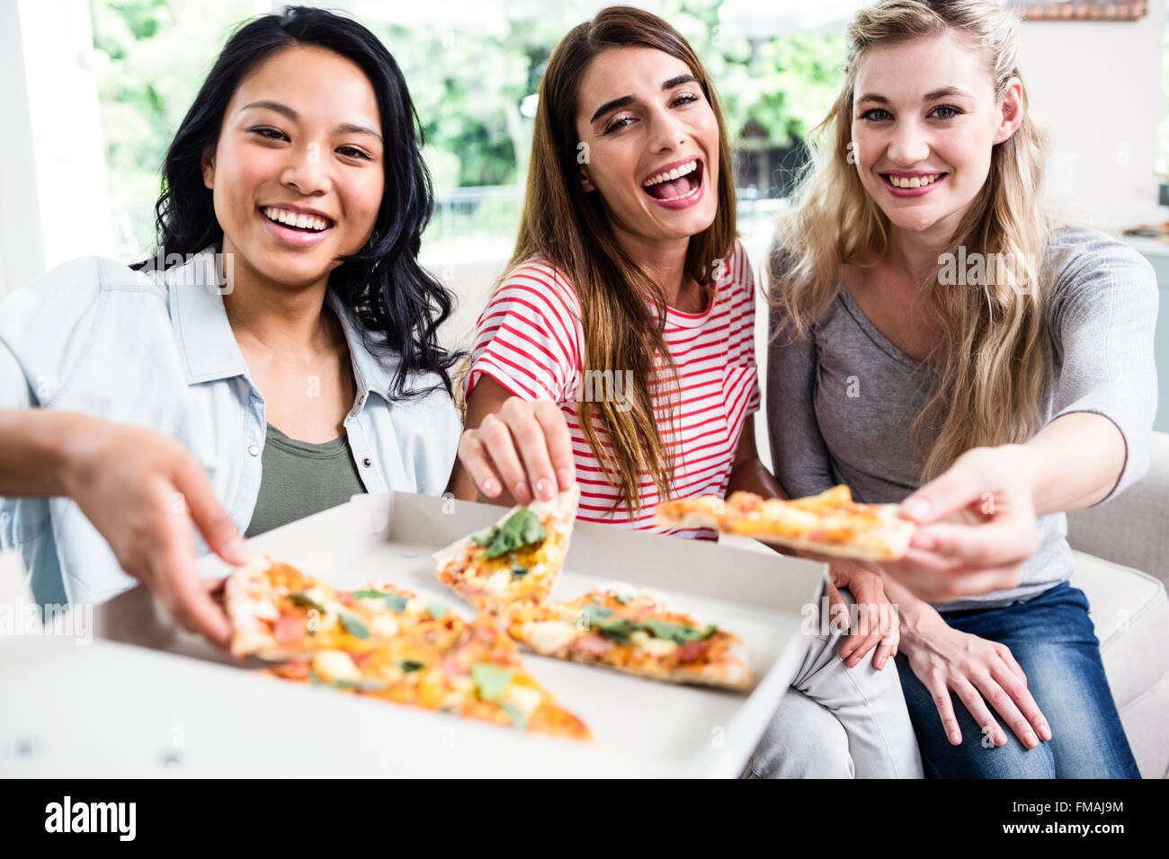 Beautiful happy female friends eating pizza Stock Photo - Alamy
