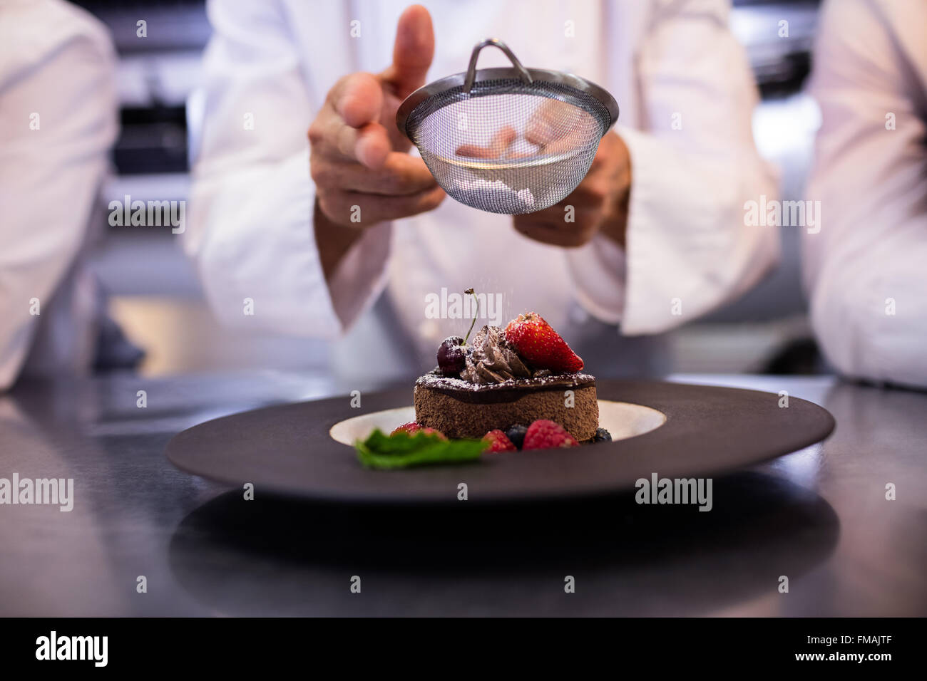 Chefs team finishing dessert plates Stock Photo - Alamy