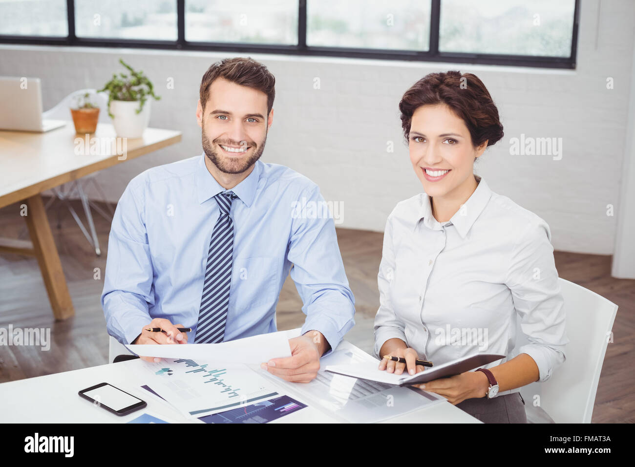 Happy business people with documents sitting in office Stock Photo - Alamy