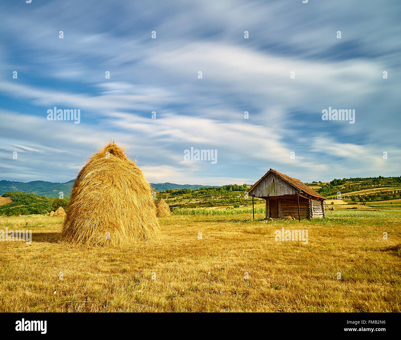 Time lapse landscape with haystack, small barn, yellow filed and ...