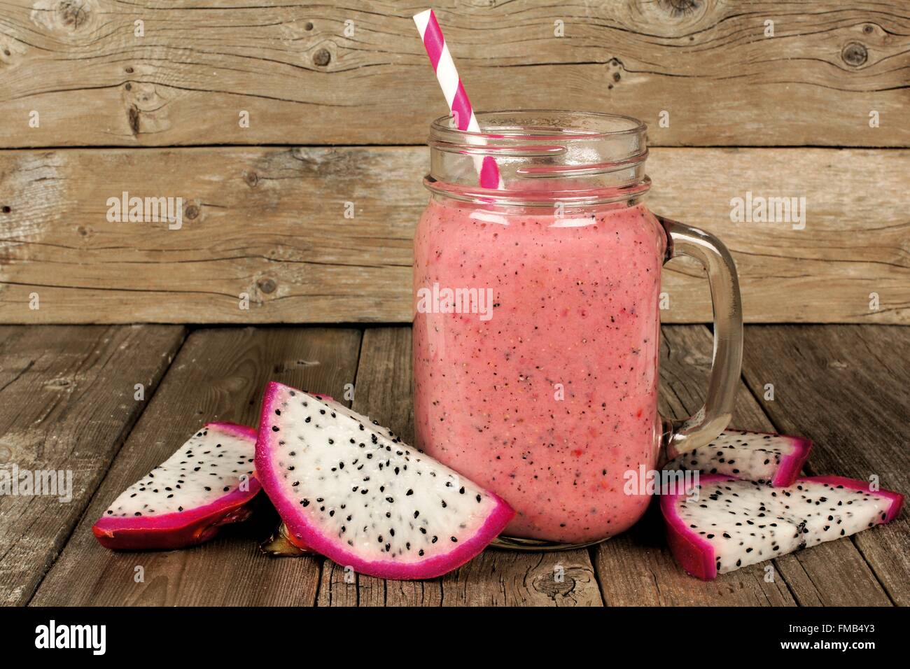 Pink raspberry, dragon fruit smoothie with fruit slices on an old wood ...