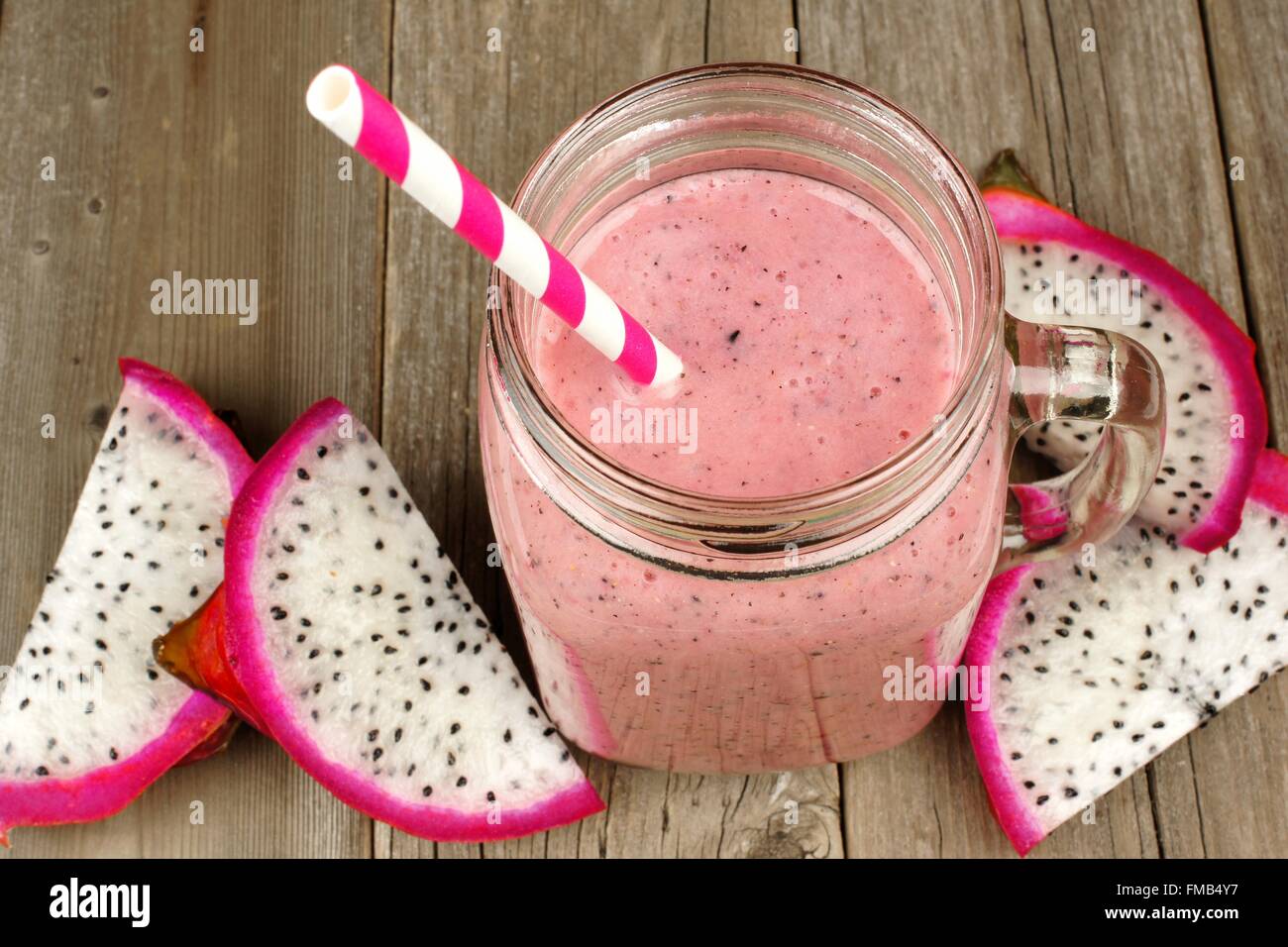 Pink raspberry, dragon fruit smoothie in jar mug on a wood background ...