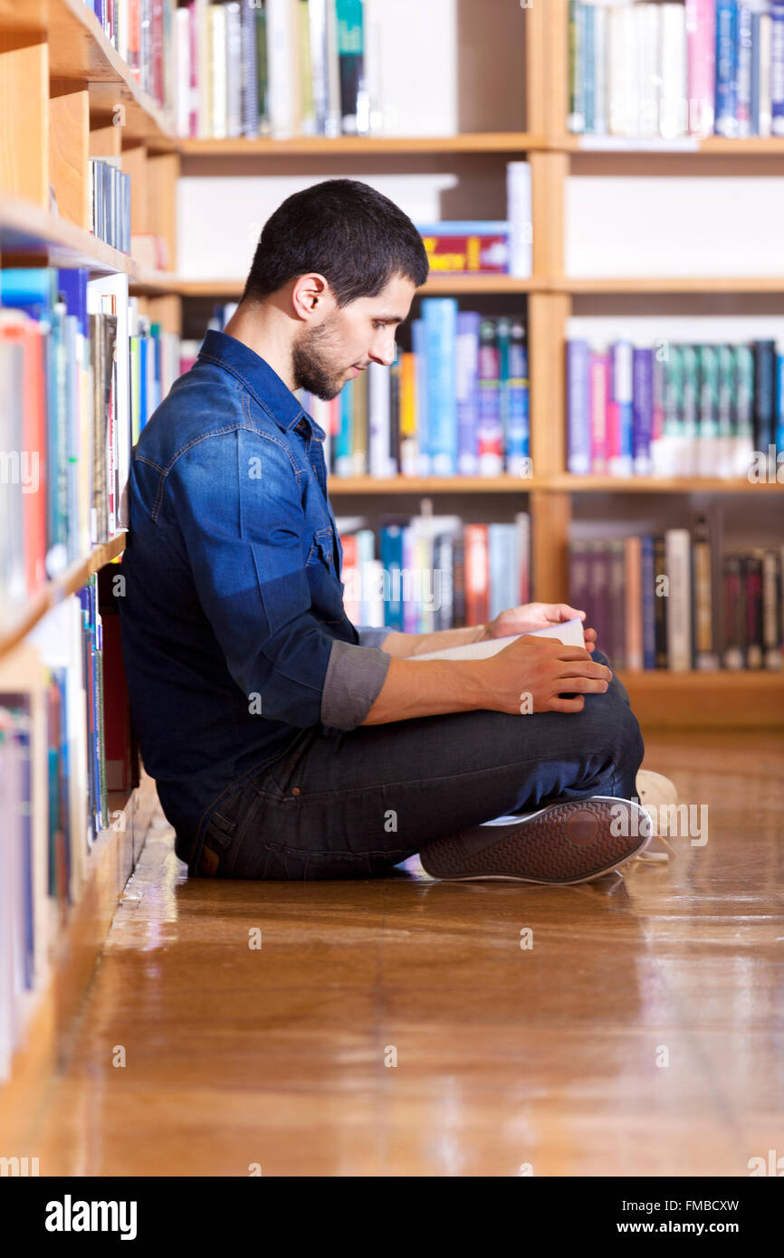 Male student reading a book at the library Stock Photo - Alamy