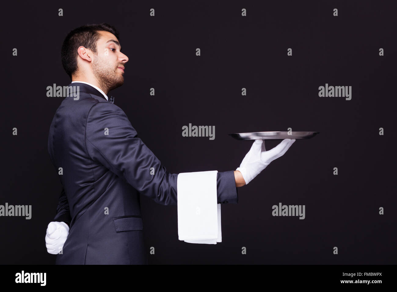 Serious waiter looking to his silver tray against dark background Stock ...