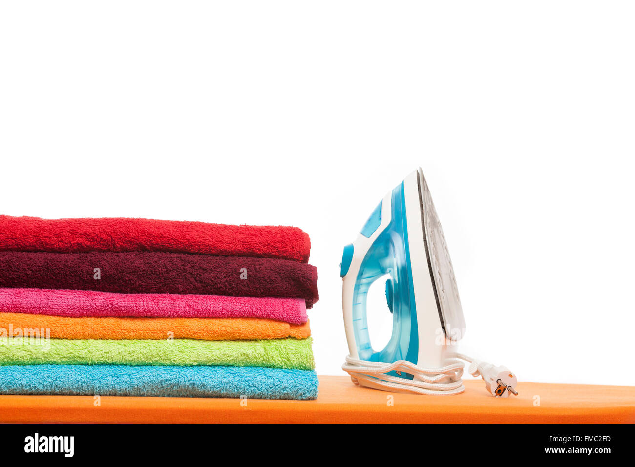 Ironing board with colorful towels on white background Stock Photo - Alamy