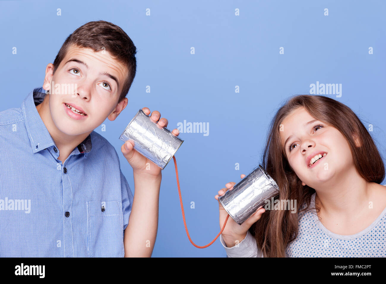 Kids playing with a can as a telephone on blue background Stock Photo ...