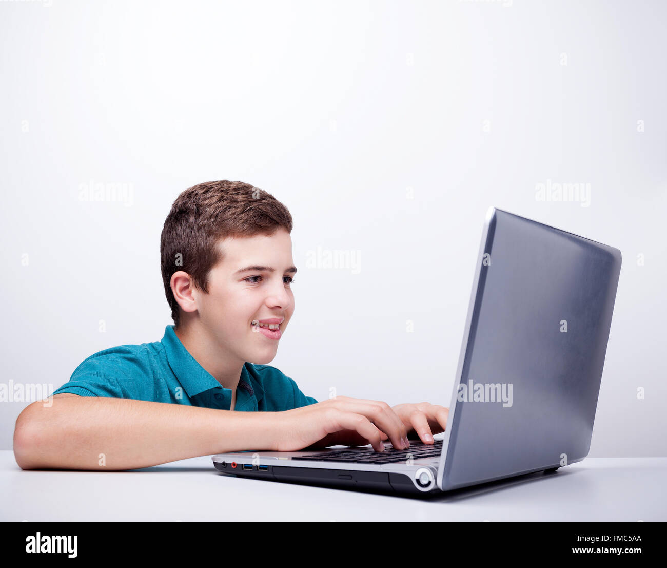 Boy using a laptop on gray background Stock Photo - Alamy