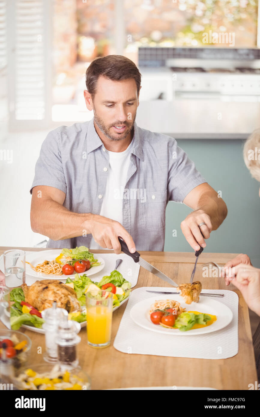 Man serving meat in plate while having lunch Stock Photo - Alamy