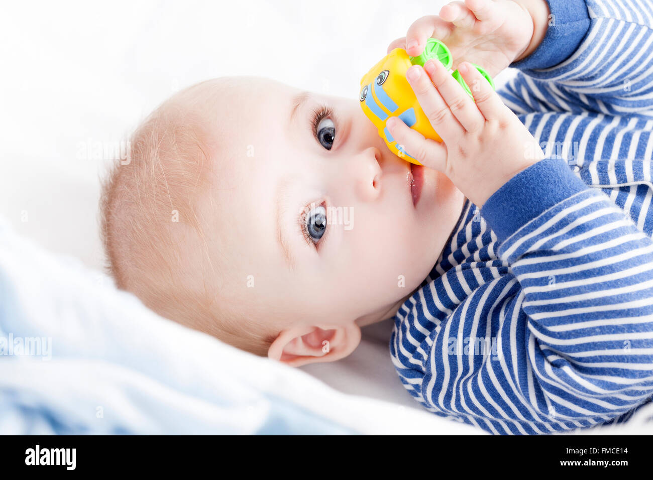 Baby with blue eyes playing with a toy Stock Photo - Alamy