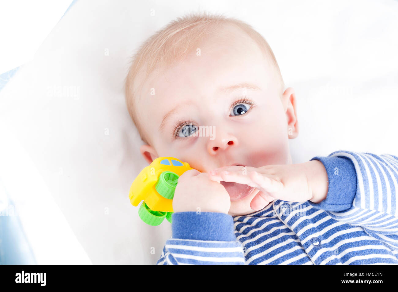 Baby with blue eyes playing with a toy Stock Photo - Alamy