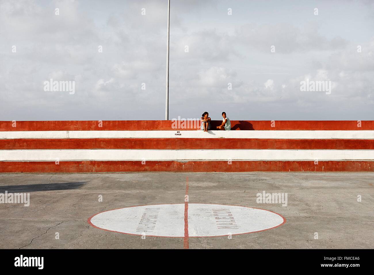 Cuba, Guantanamo, Baracoa, Girls sitting on the steps of an empty ...
