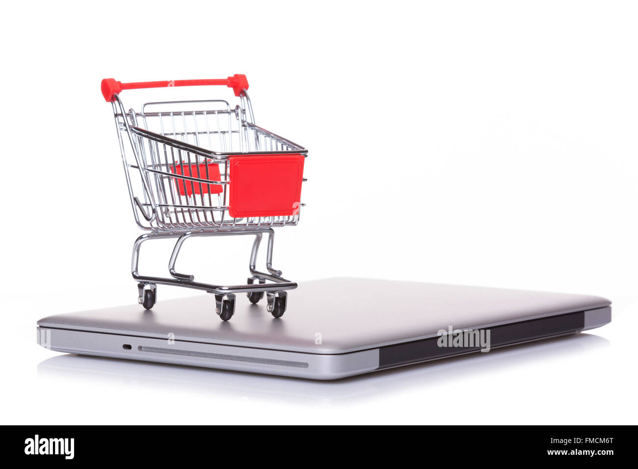 Shopping cart over a laptop computer, isolated on white background ...