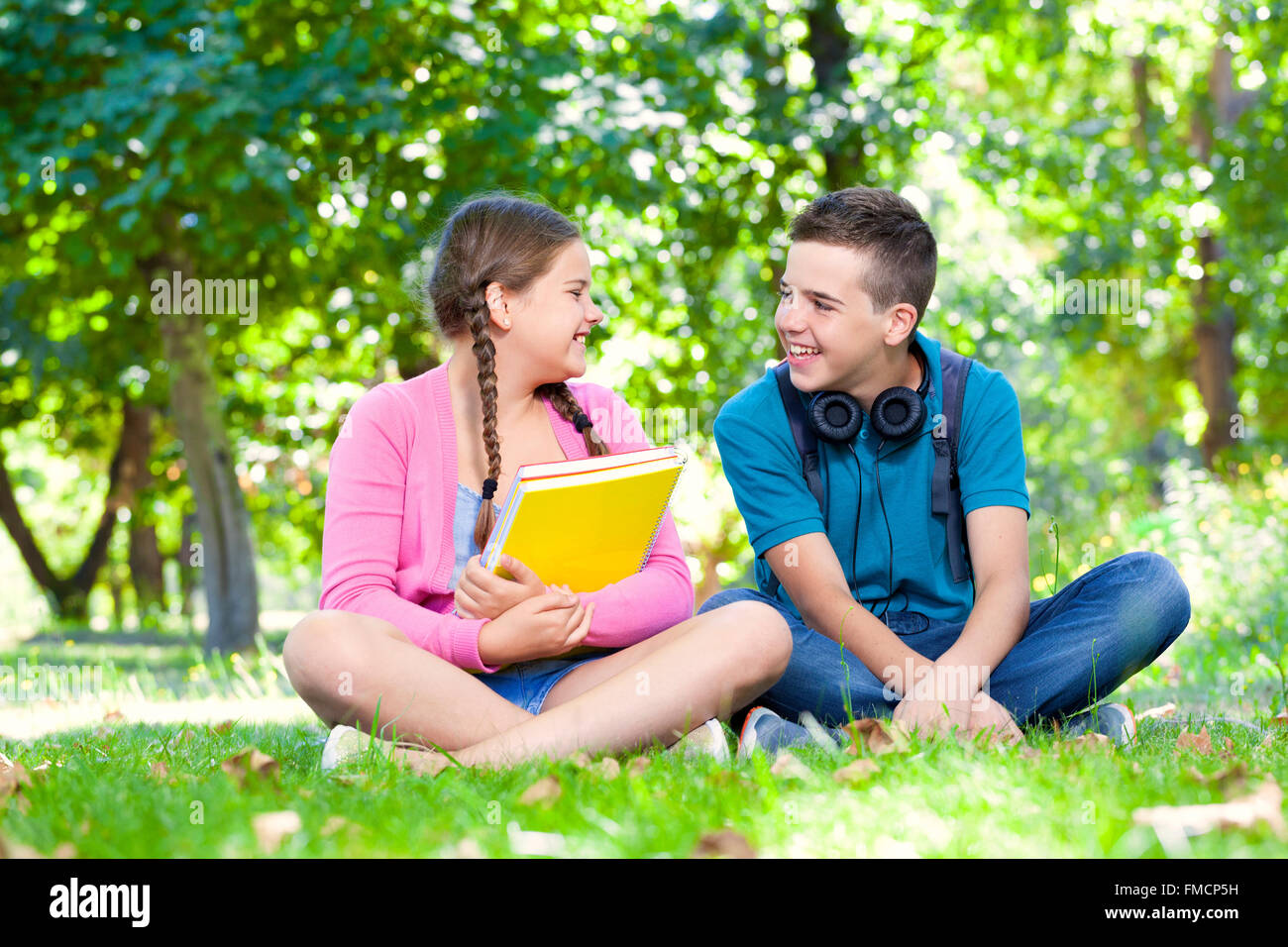 Smart kids sitting on the grass looking happy Stock Photo - Alamy