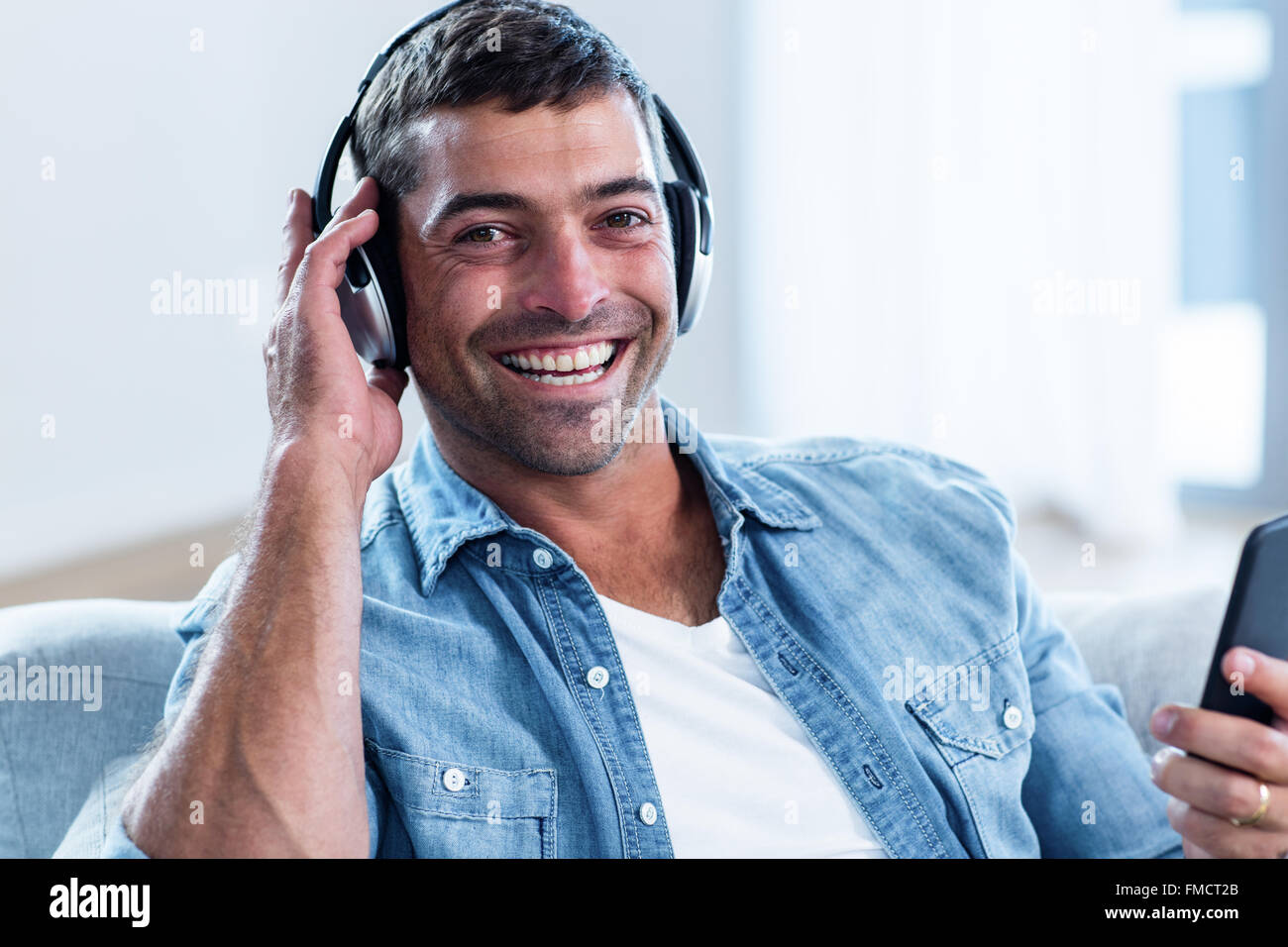 Young man listening to music while using mobile phone Stock Photo - Alamy