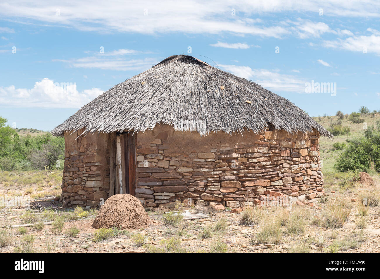 A hut with thatched roof built from stone next to the road between ...