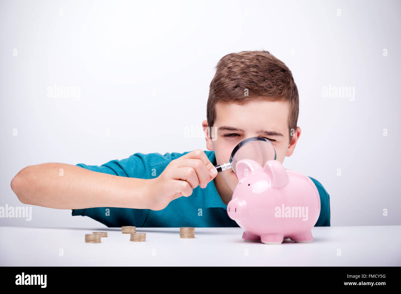 Boy with magnifying glass looking to his savings Stock Photo - Alamy