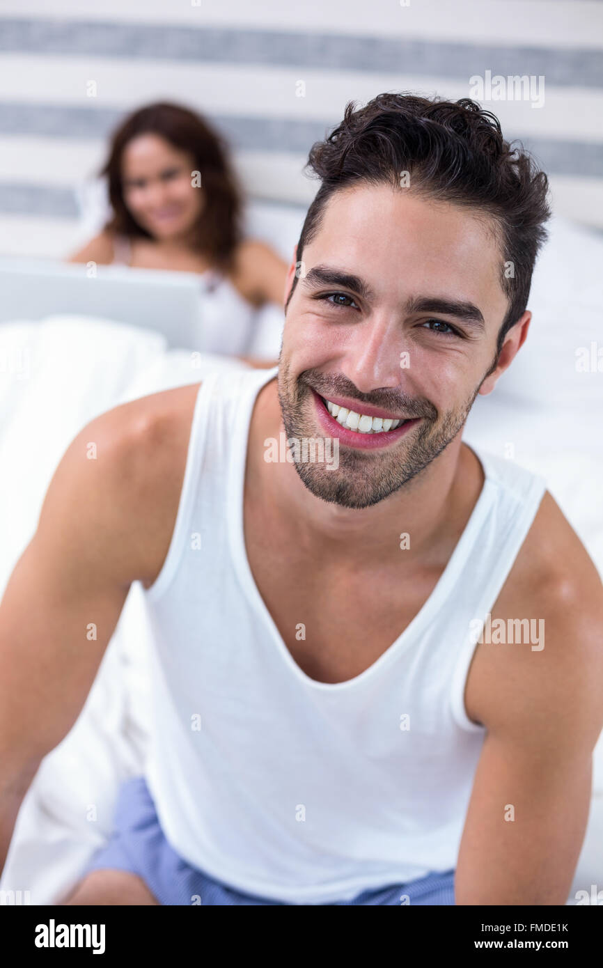 Man smiling while wife sitting on bed in background Stock Photo - Alamy