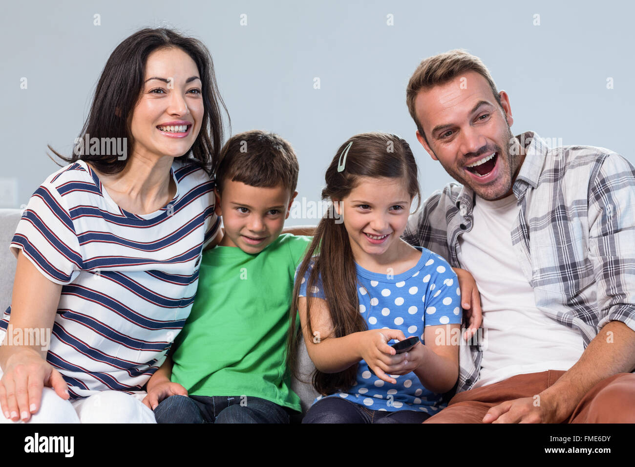 Happy family watching television with their two children Stock Photo ...