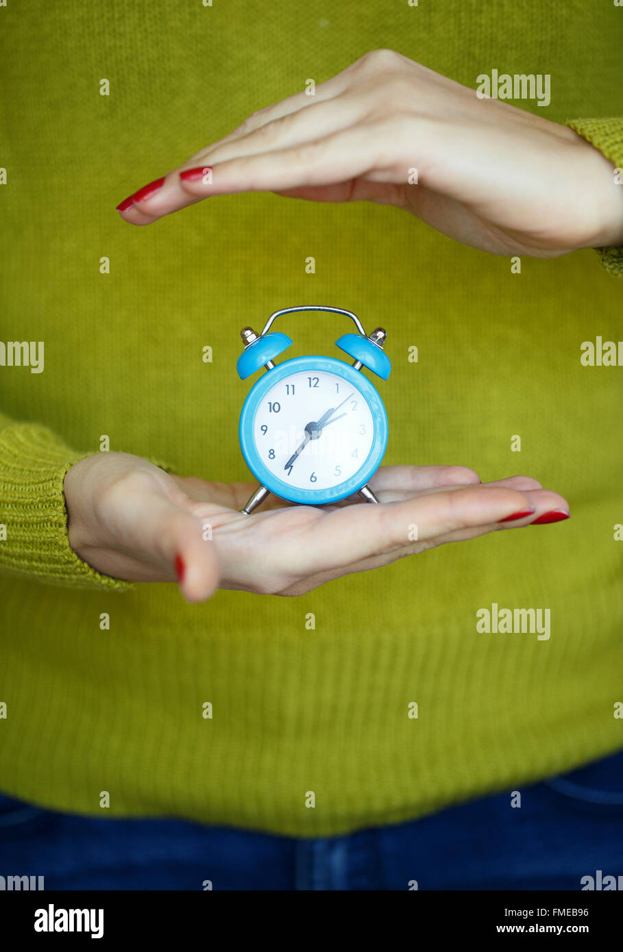 Little blue alarm clock in the hands of woman, the concept of saving ...