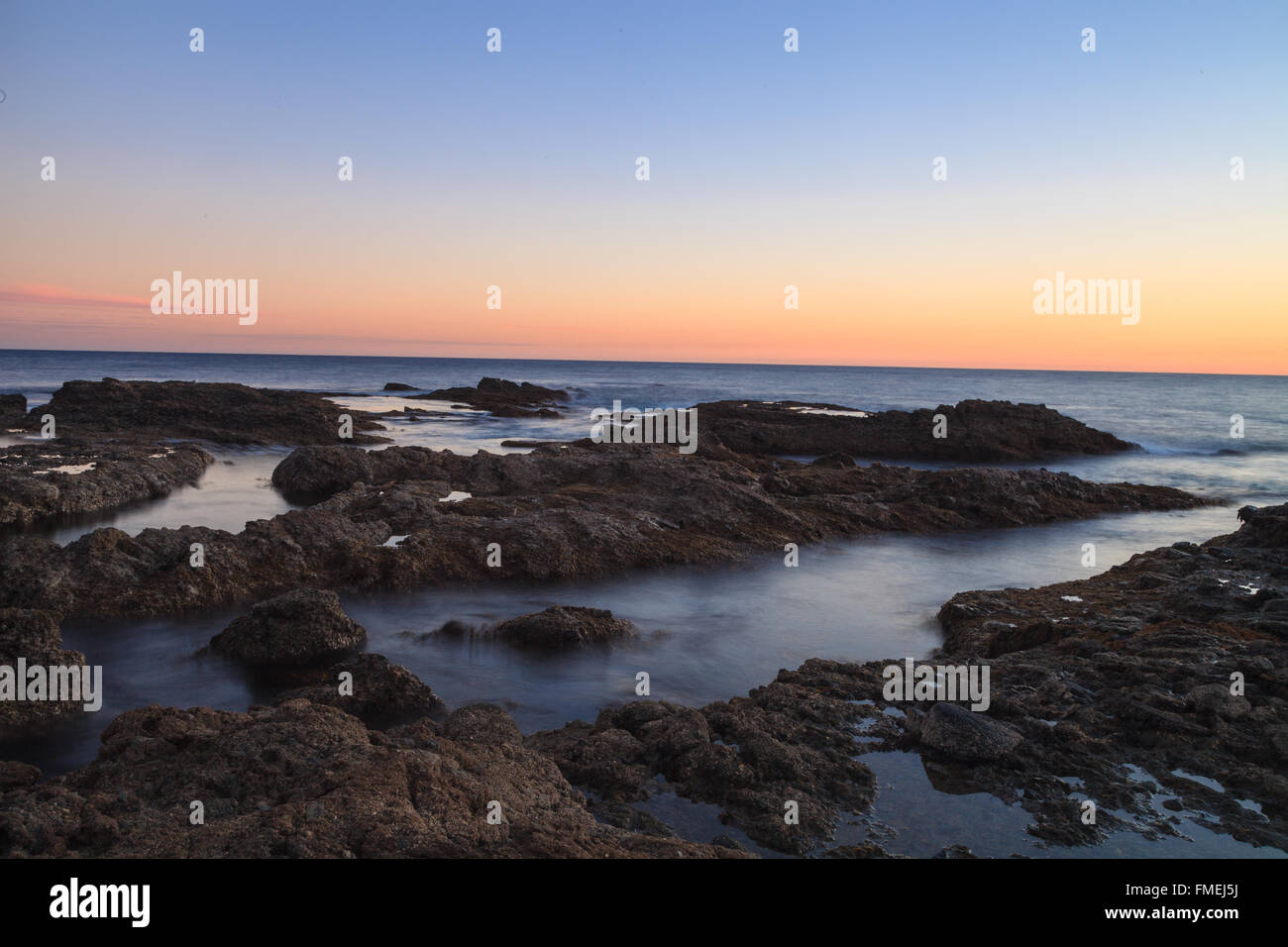 Long exposure of sunset over rocks, giving a mist like effect over ...