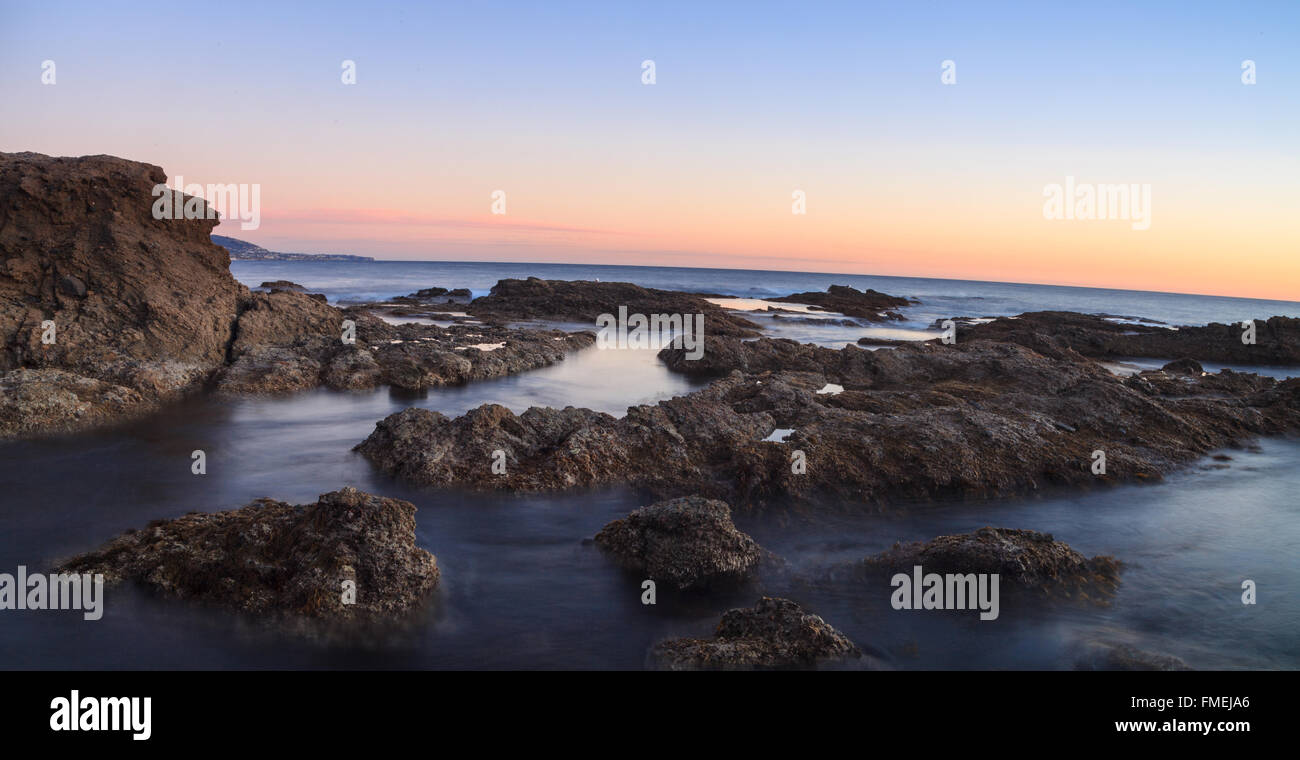 Long exposure of sunset over rocks, giving a mist like effect over ...