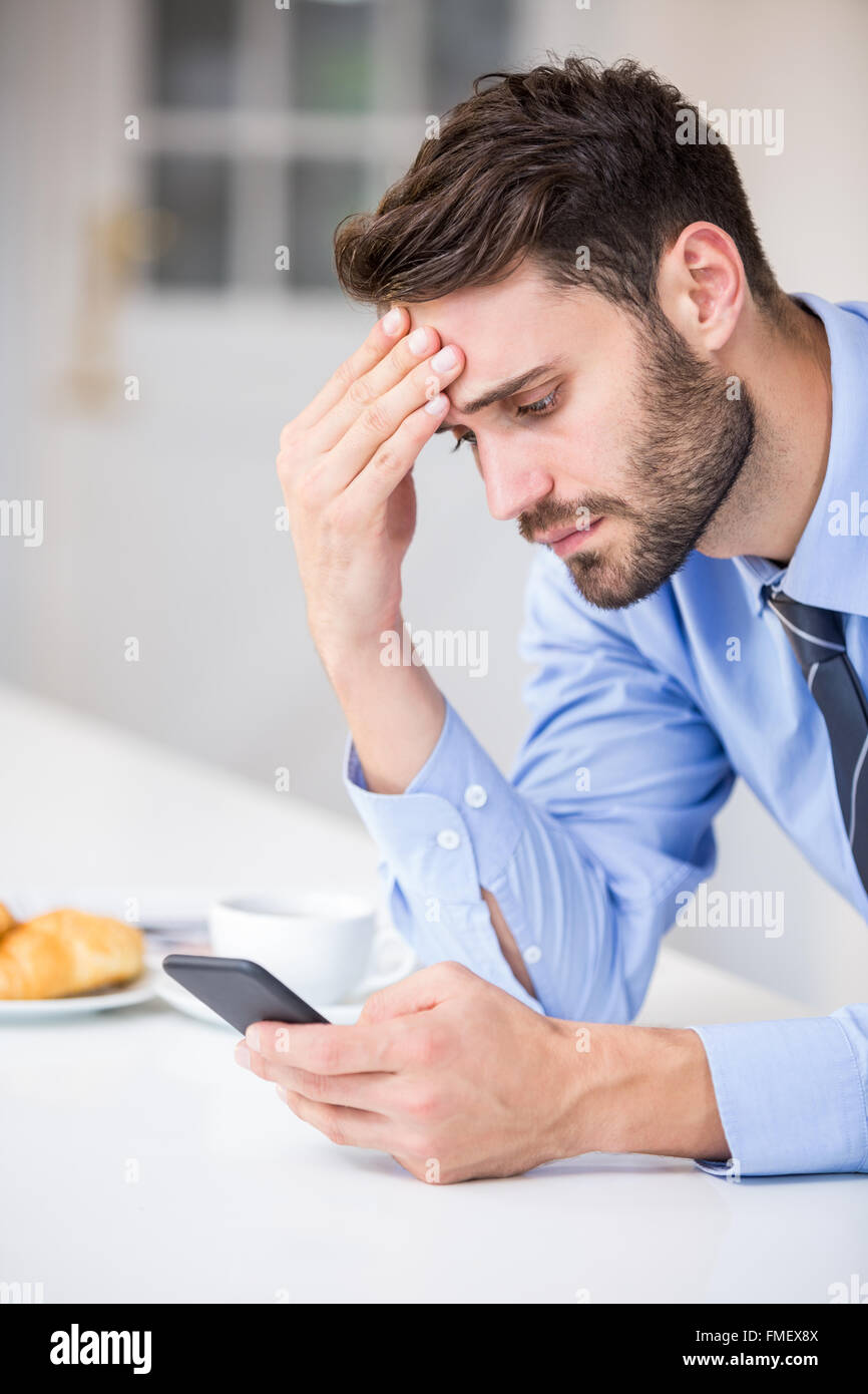 Tensed businessman using mobile phone by table Stock Photo - Alamy