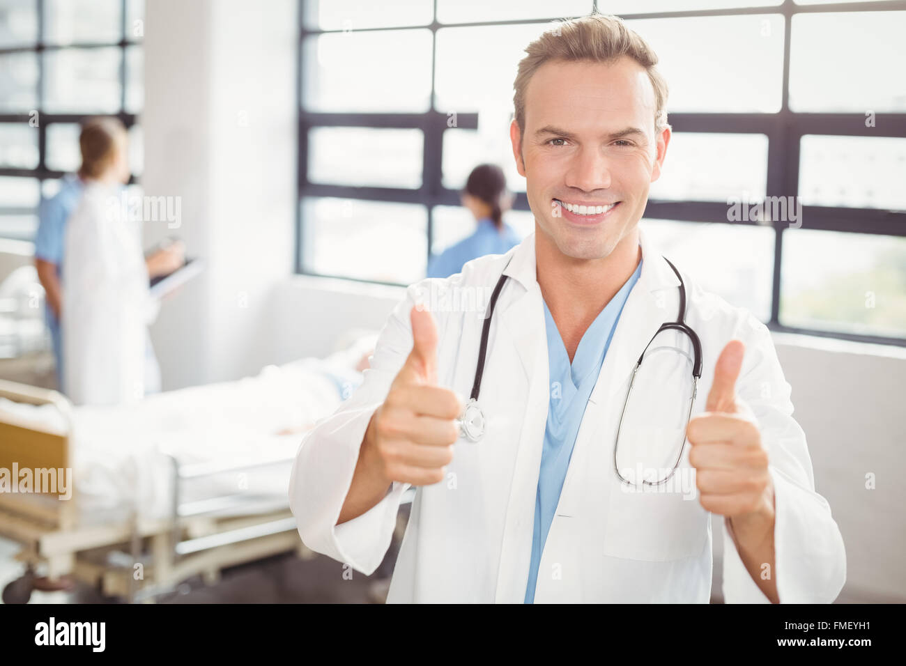 Portrait of doctor giving thumbs up and smiling Stock Photo - Alamy