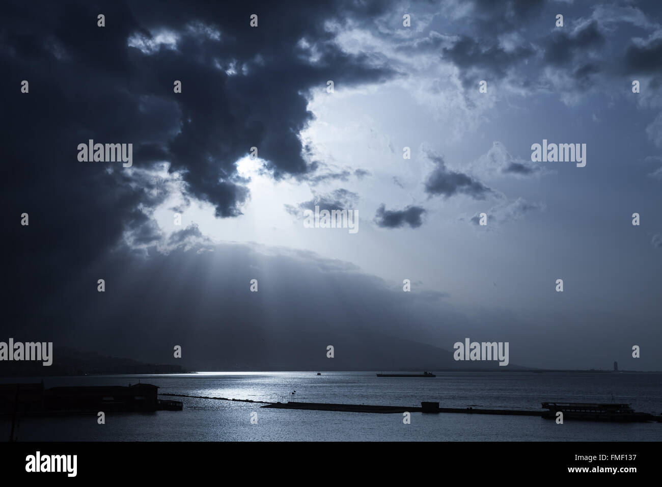 Sunlight goes through dark stormy clouds. Bay of Izmir, Turkey. Blue ...