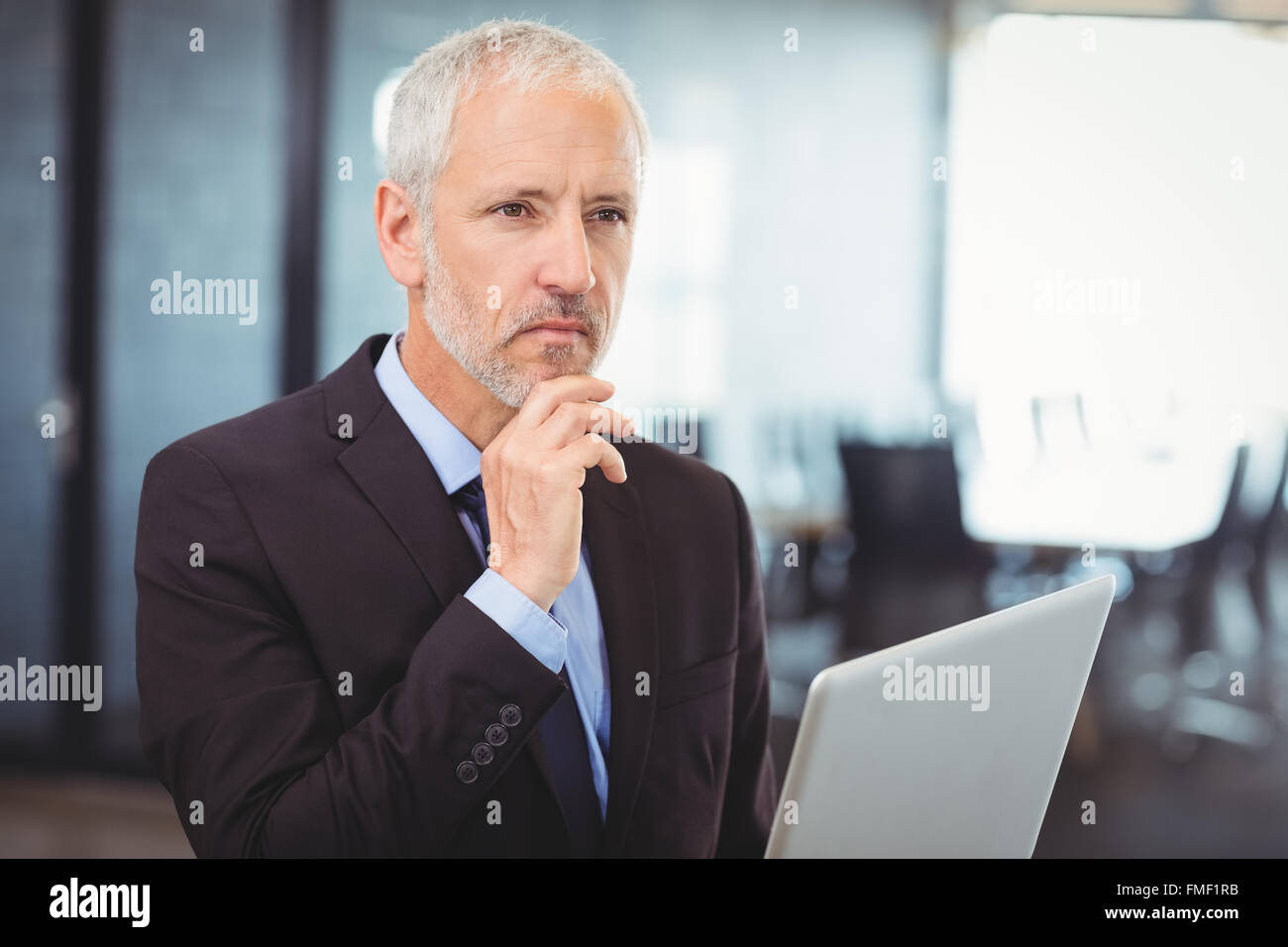 Businessman thinking while working on laptop Stock Photo - Alamy