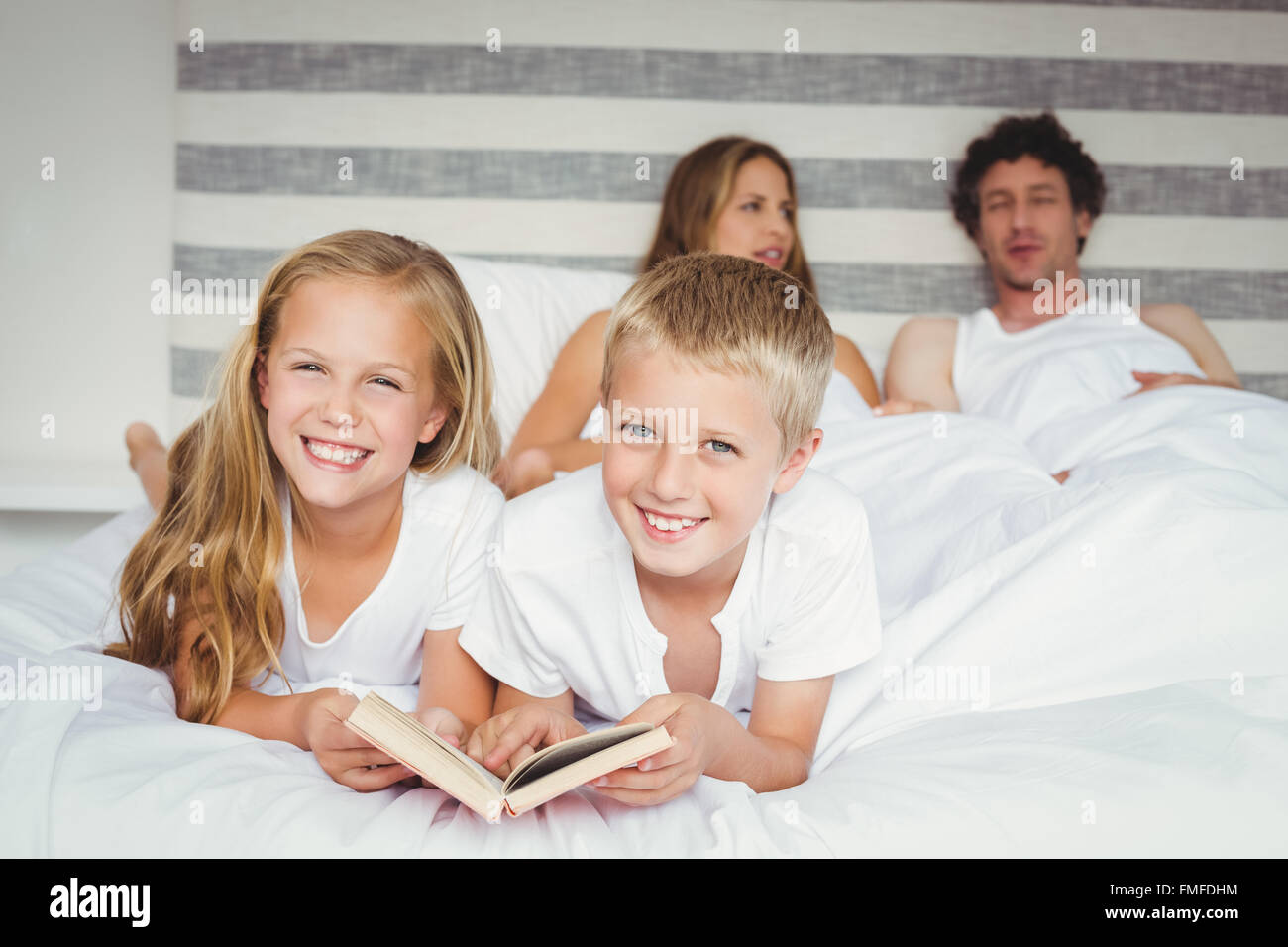 Portrait of siblings relaxing with parents on bed Stock Photo - Alamy