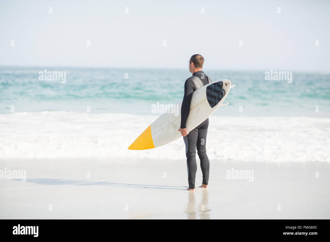 Surfer standing on the beach with a surfboard Stock Photo - Alamy