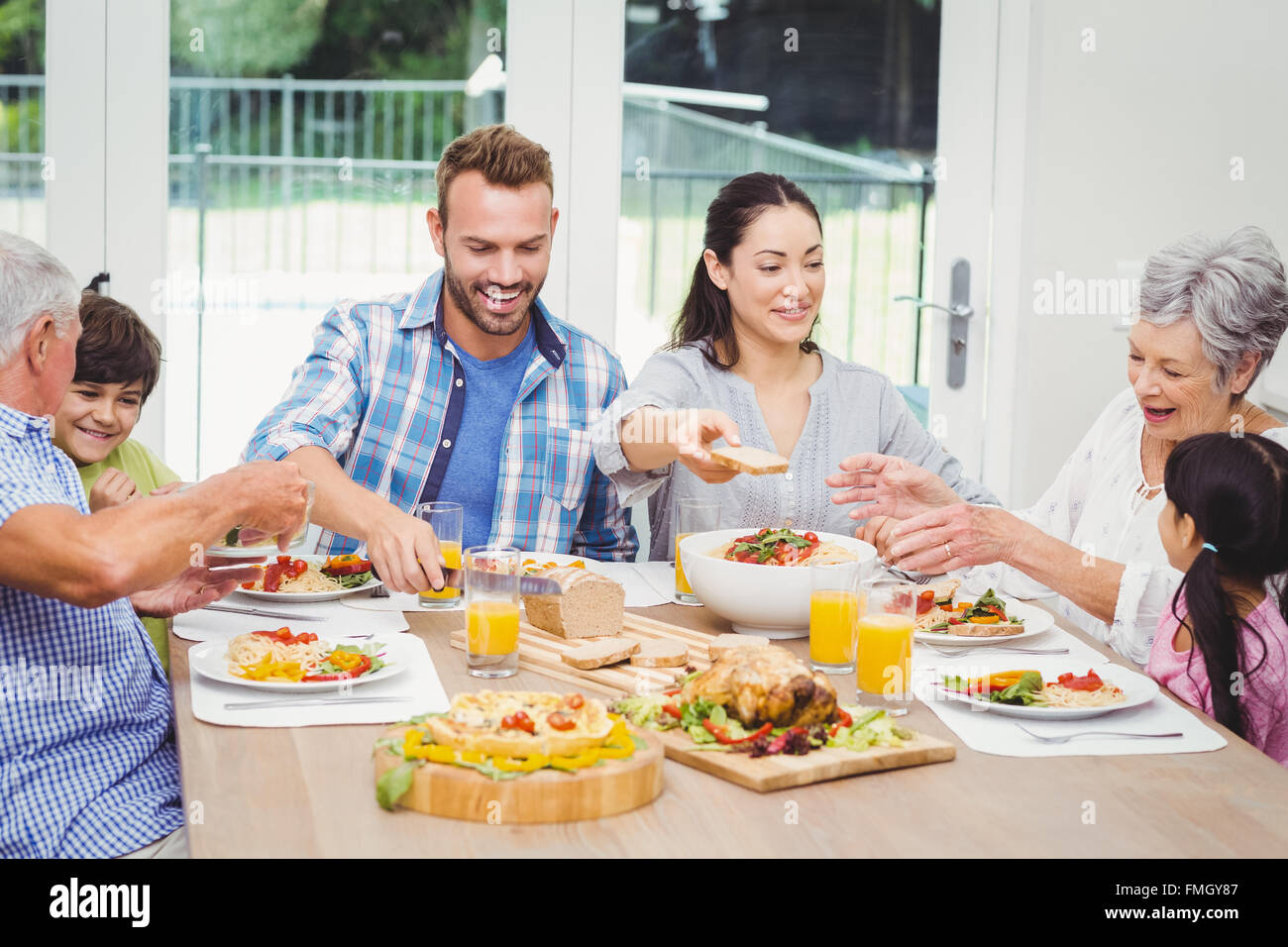 Smiling multi generation family having food at dining table Stock Photo ...
