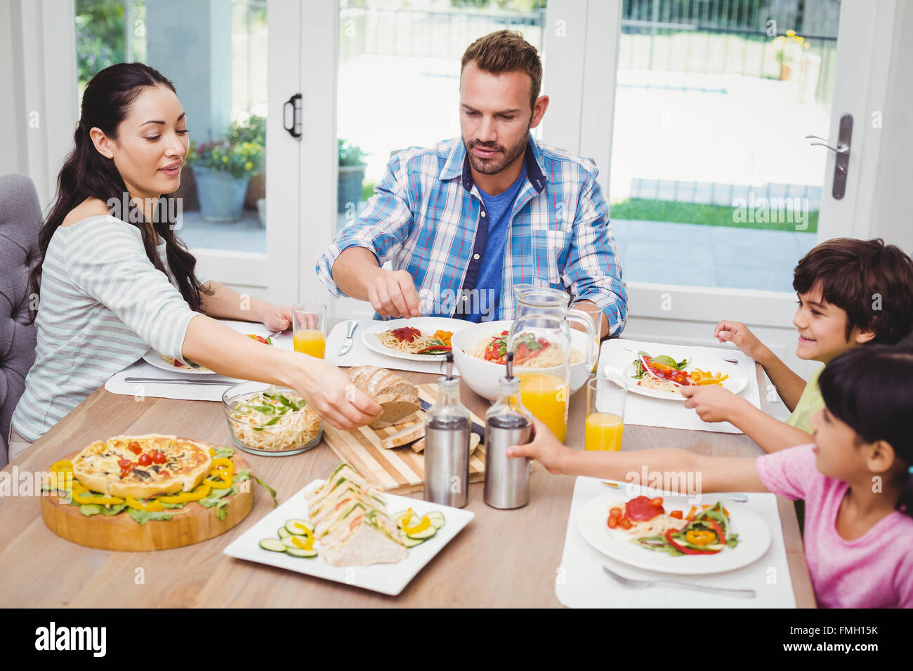 Family having food while sitting at dining table Stock Photo - Alamy