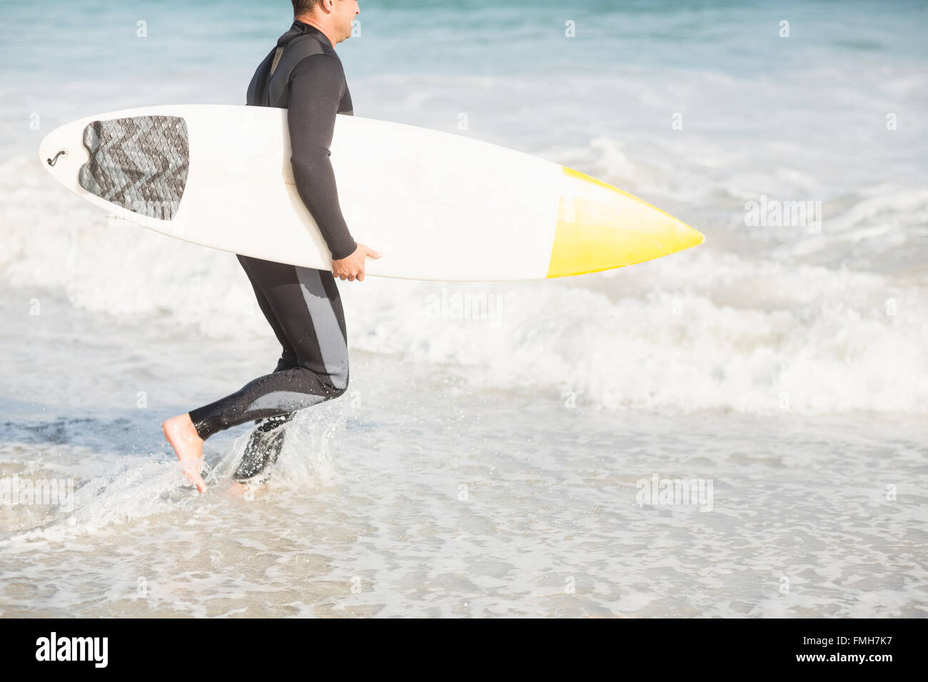 Surfer walking on the beach with a surfboard Stock Photo - Alamy