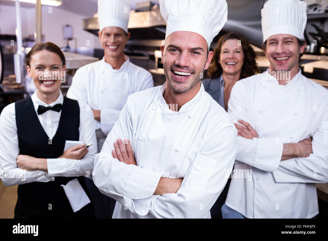 Happy restaurant team standing together with arms crossed in commercial ...