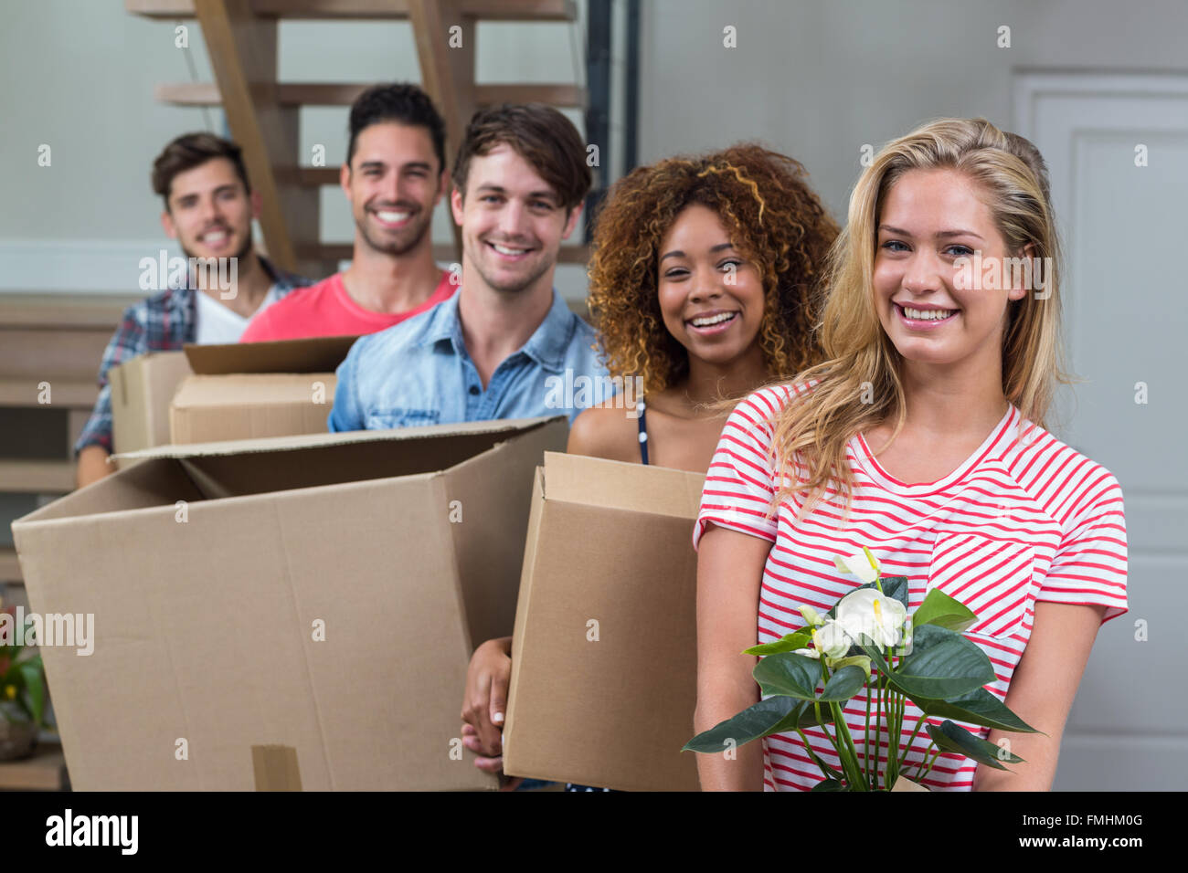 Friends smiling while carrying boxes in new house Stock Photo - Alamy