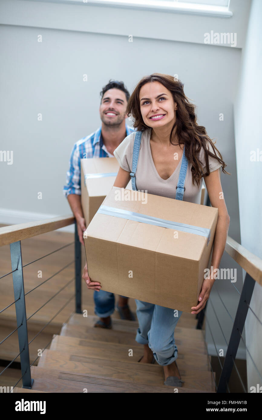 Smiling couple holding cardboard boxes while climbing steps Stock Photo ...