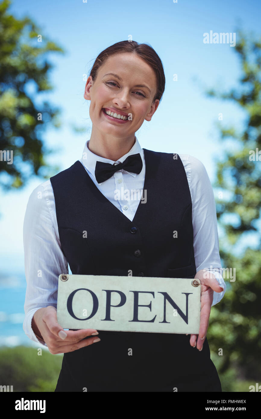 Smiling waitress holding open sign Stock Photo - Alamy