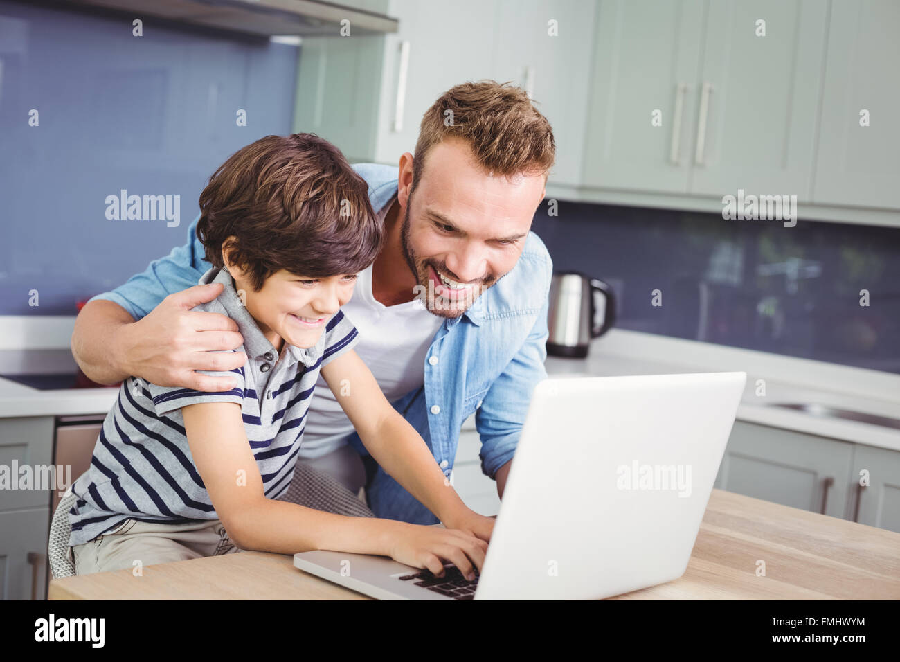 Smiling father and son working on laptop Stock Photo - Alamy