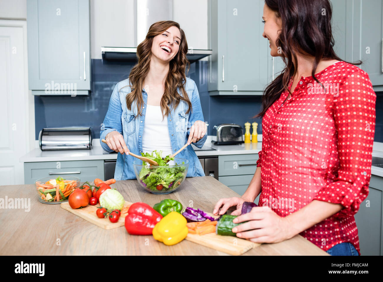 Smiling female friends preparing salad Stock Photo - Alamy