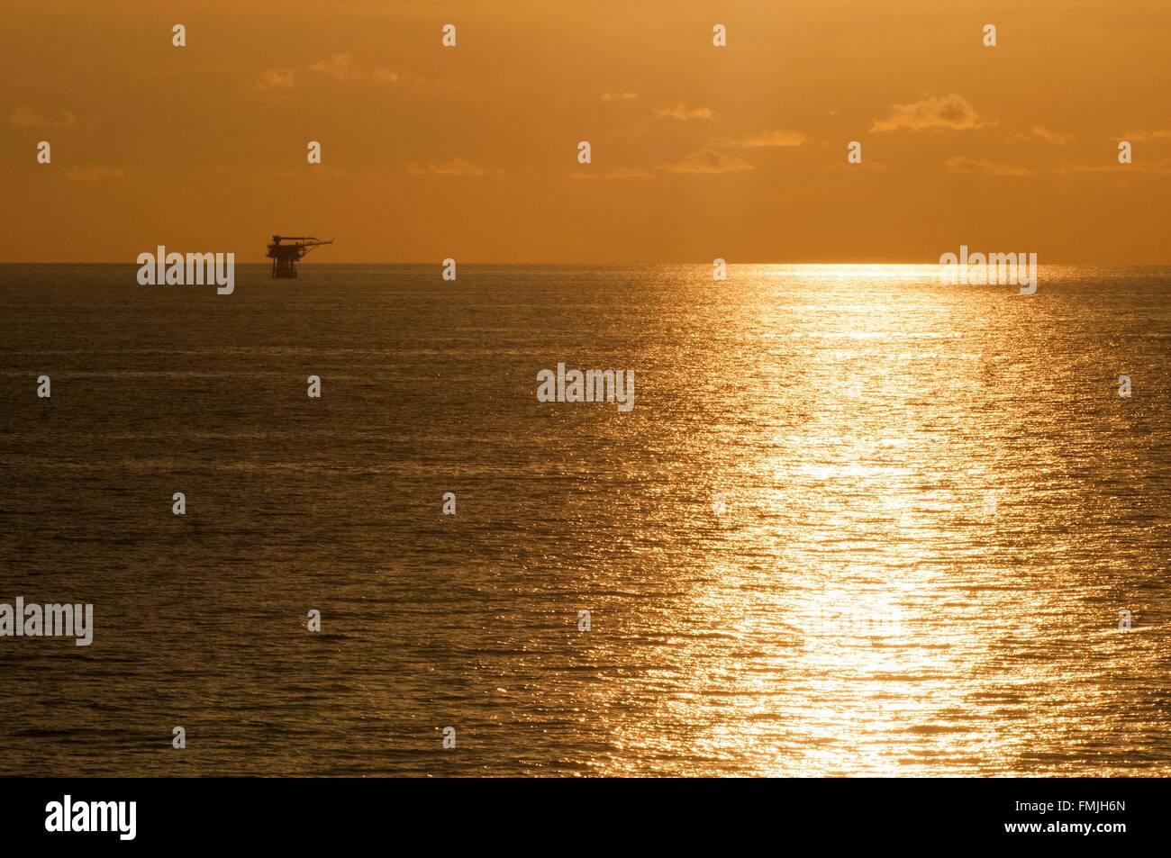 sunset over seascape and oil rig Stock Photo - Alamy